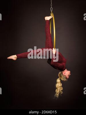 Aerial performer in a gold costume suspended against a vibrant sunset ...