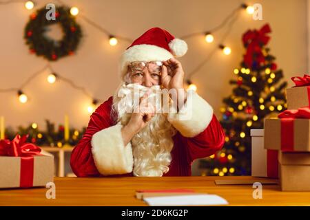 Santa Claus showing shh secret gesture on Christmas eve sitting at home ...