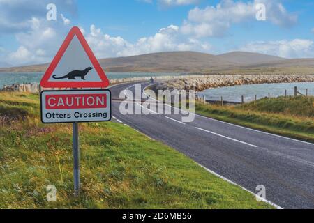 Caution Otters Crossing red triangle road sign by causeway from ...