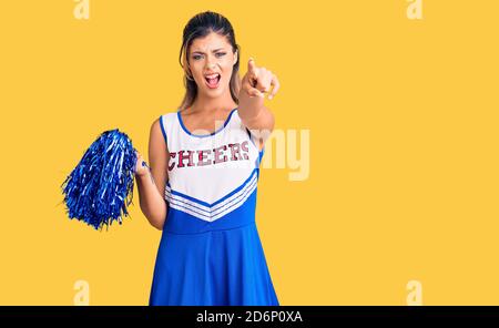 Young beautiful woman wearing cheerleader uniform sticking tongue out ...