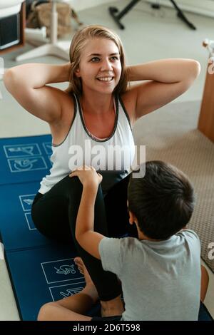 Young boy do abs crunches while holding football in his hands and legs ...