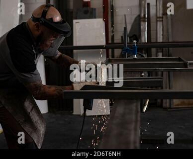 Side view of serious male welder using electric grinder and cutting ...