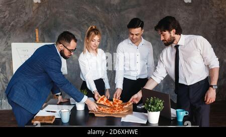Happy diverse colleagues spend work break together eating takeaway ...