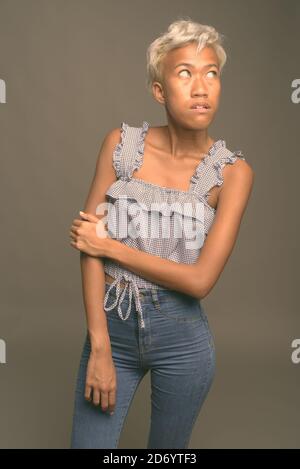 Young beautiful rebellious woman with short hair against gray ...