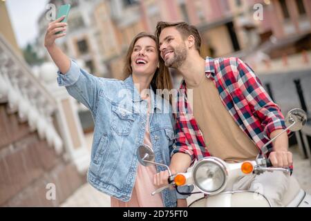 Woman taking a selfie with her boyfriend and a scooter Stock Photo - Alamy