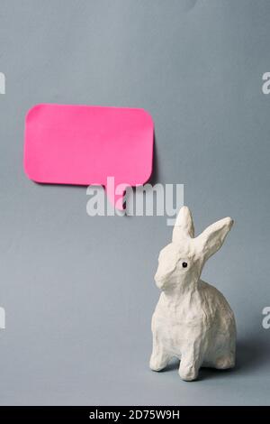 White Easter bunny with pink sticky note on gray background decoration ...