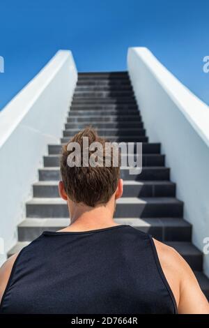 Fitness man looking ahead at stairs climbing challenge. Runner going up ...