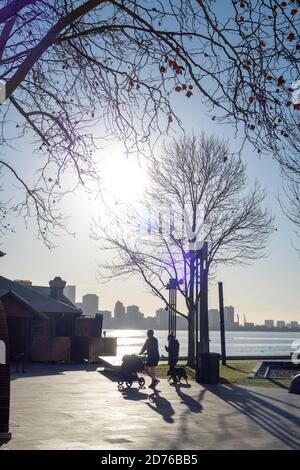 A young family with a baby in a stroller admire a view of a river while ...