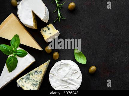 Different types of cheese on a black graphite board decorated with ...