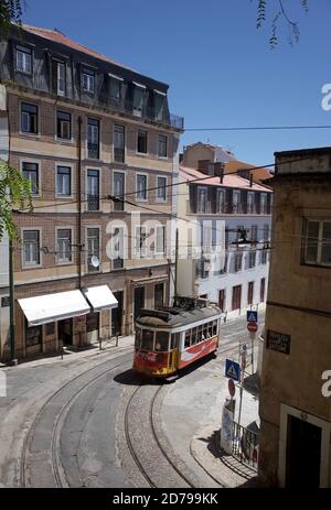 A classic yellow-and-red Lisbon tram travels through Praça do Comércio ...
