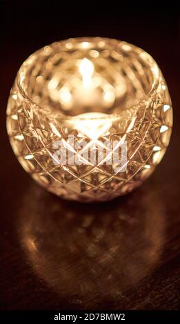 Burning candle on wooden table in dark room Stock Photo - Alamy