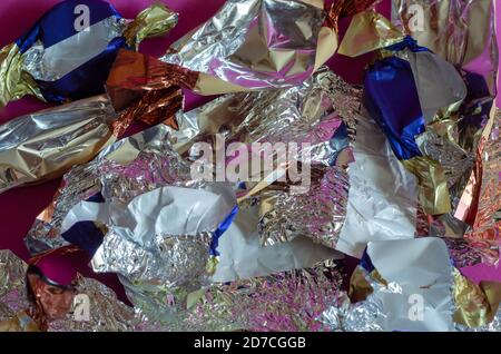 Lots of crumpled shiny candy wrappers on pink background. Empty chocolate candy wrappers ...