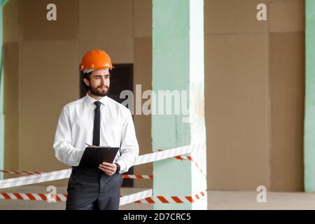A worker in a construction helmet checks a clipboard Stock Photo - Alamy