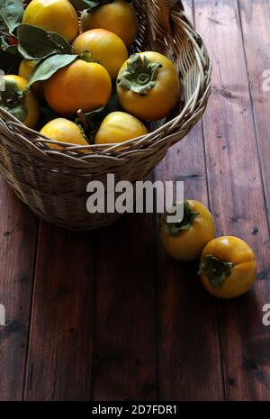 Fresh persimmons on wicker basket isolated on wooden table. Top view ...