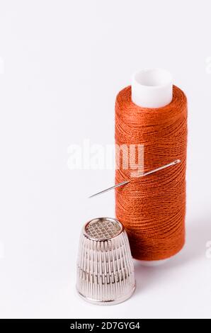 Spool of Orange Thread and Thimble on Orange and White Fabric With ...