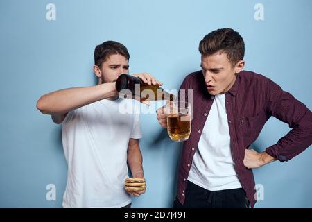 Two cheerful drunk friends drinking beer lifestyle emotions on a blue ...