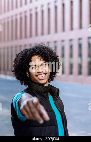Young hispanic man pointing up with fingers smiling and laughing hard ...