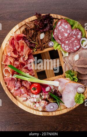 cold cuts of sausage delicacies on a wooden round stand Stock Photo - Alamy