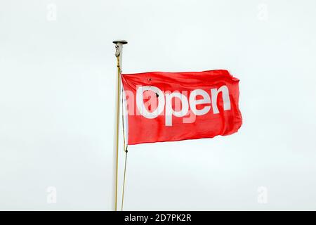 Red flag with the word open, flying in the wind at the seaside town of ...