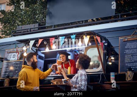 friends having a toast with a employee in fast food service, plastic ...