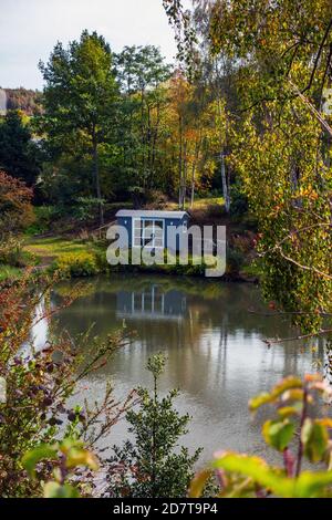 pretty private garden with lake and shepherds hut in autumn Stock Photo ...