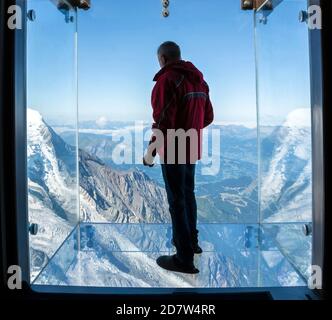 Tourist stands in the 'Step into the Void' glass box on the Aiguille Du ...