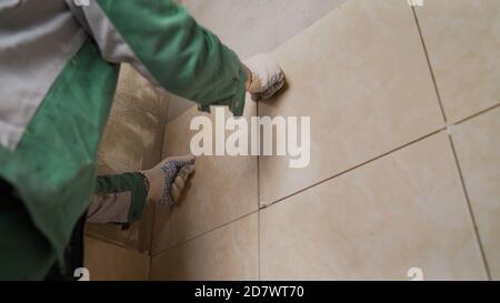 The master puts tiles on the wall. Master in overalls puts ceramic ...
