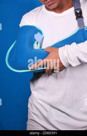Young man with broken arm in sling smiles, raising thumb near empty ...