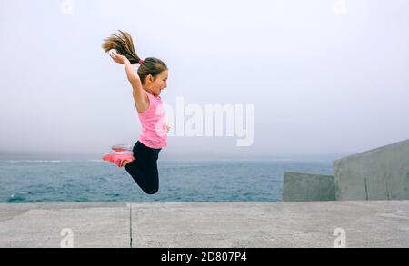 Little girl jumping by sea pier Stock Photo - Alamy