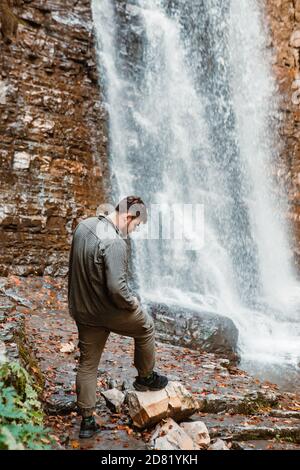 young strong man hiker looking the waterfall copy space Stock Photo - Alamy