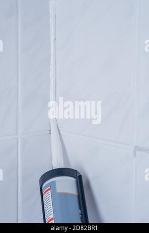 Plumber Applying silicone sealant to the tile joint Stock Photo - Alamy
