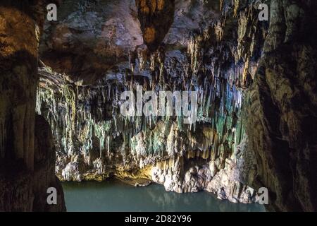 A large cave with a blue river running through it. The cave is very ...