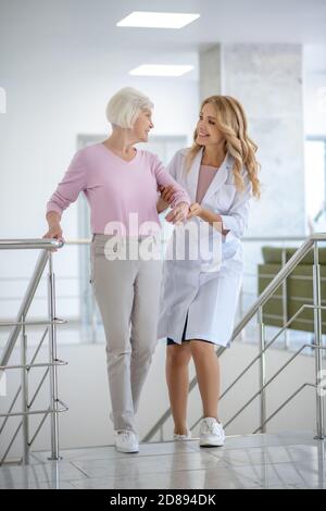 Doctor in a lab coat supporting her patient and looking at her Stock ...