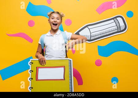amazed child point finger on shampoo bottle on yellow background ...
