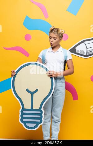 amazed kid with school backpack on yellow background, school Stock ...