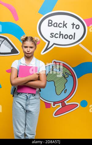 skeptical schoolgirl holding speech bubble with student lettering near ...