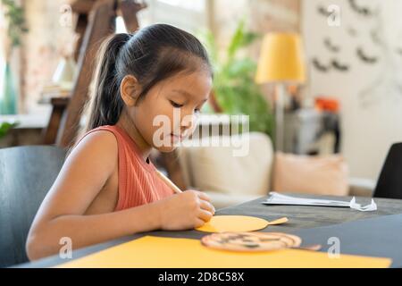 Beautiful children sitting at table, concentrated on decorating eggs ...