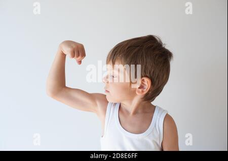 strong small child in tank top showing his muscle with grimace on his ...