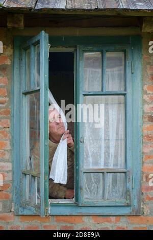 miserable looking older male curtain twitcher spying on neighbours from ...