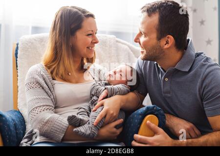 Parents and Baby having wonderful time sit on chair one the bedroom ...