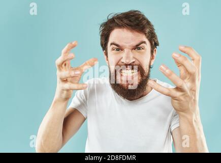 Impulsive man on a blue background gestures with his hands irritability ...