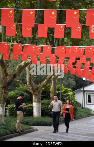 National flags fly on the street, under which vehicles and pedestrians ...
