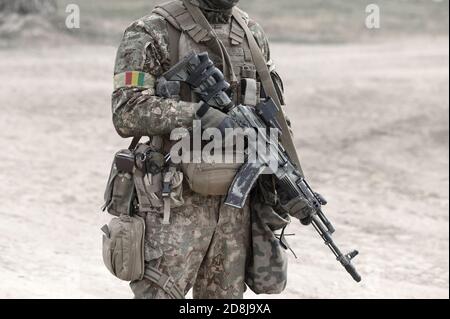 Soldier with assault rifle and flag of Guinea-Bissau on military ...