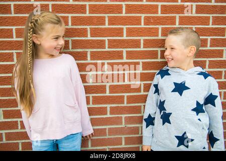 Schoolgirl standing against white brick wall background. Child girl in ...