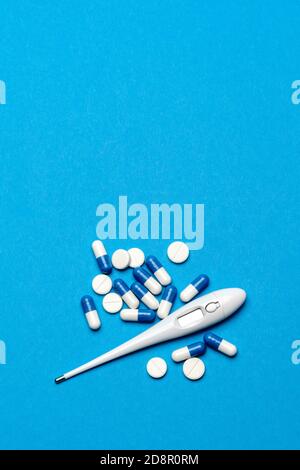 White Pills or Tablets with Electronic Thermometer on Pink Background ...