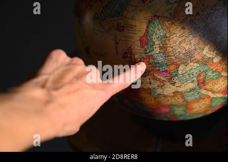 Finger pointing at vintage globe map. Hand touching world globe with ...