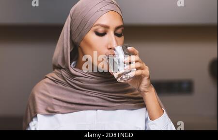 Young pretty Muslim woman with glass of coffee resting in chair and ...
