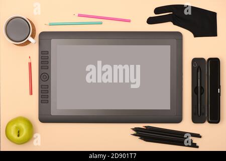 Graphic monitor stylus on peachy color table. Black tablet computer ...