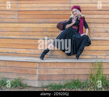 beautiful woman sits on a wooden swing with a bouquet of red roses in ...