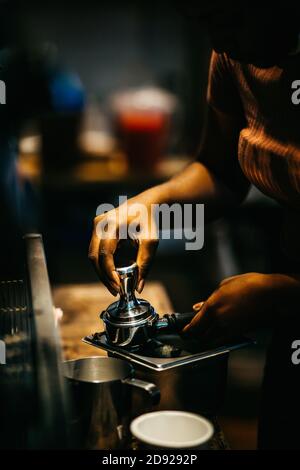 Vertical shot of barista, girl in coffee shop, pouring water in kettle ...